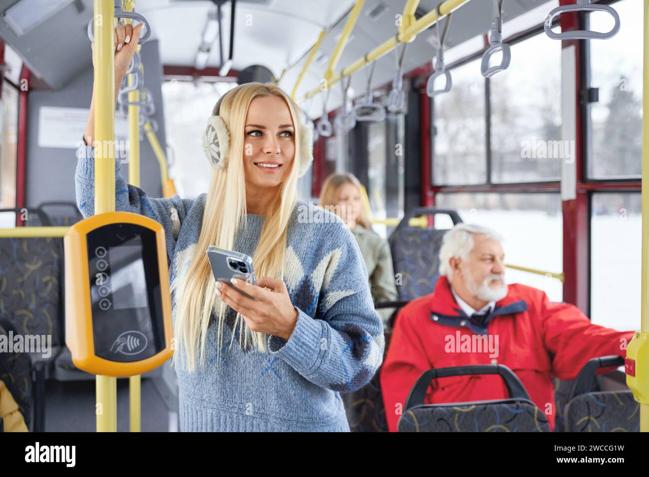 Front view of young blonde girl standing inside bus looking at window ...