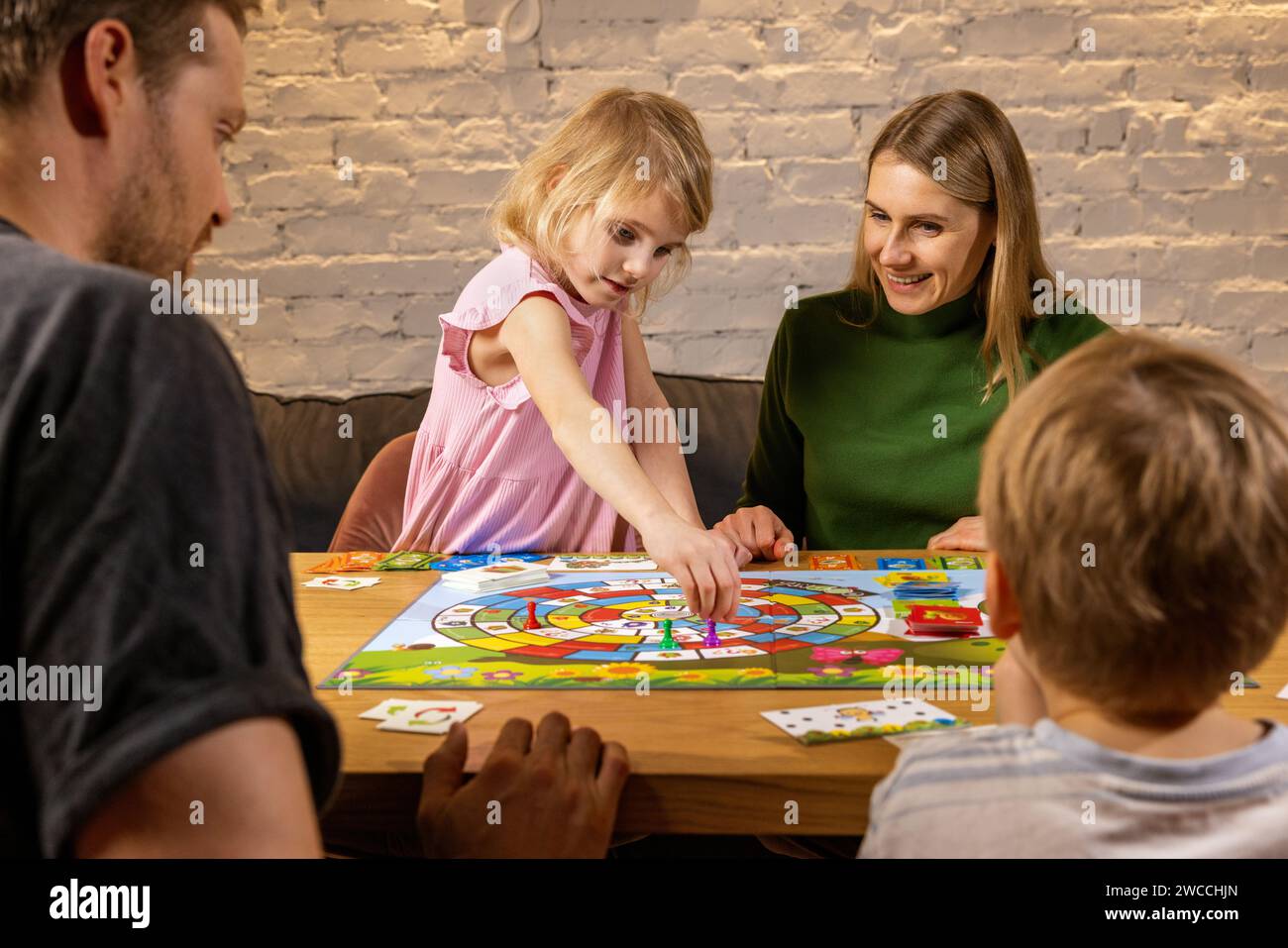 family with two children spending time together and and playing board ...