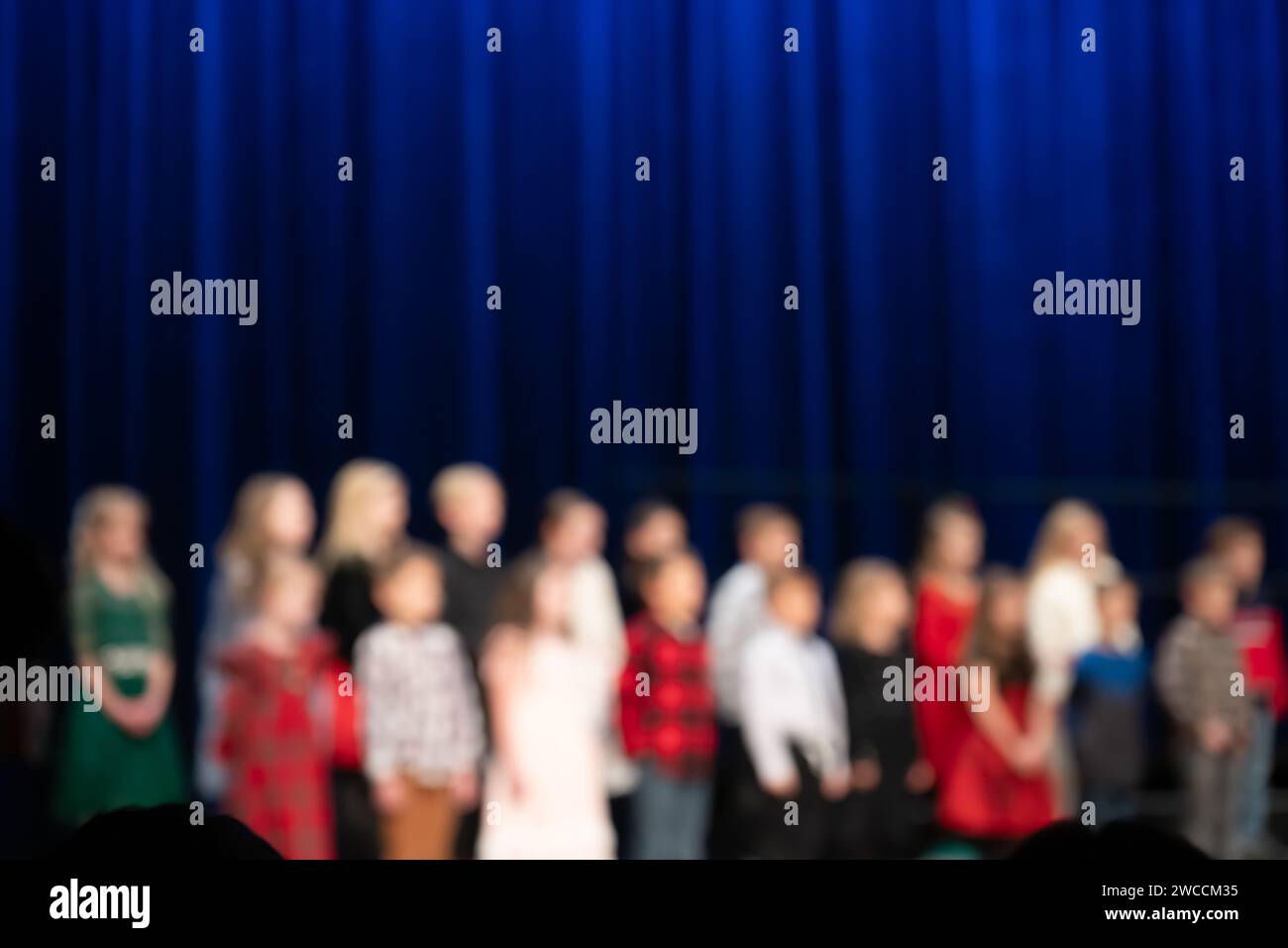 defocused elementary musical concert with children lined up on stage to ...