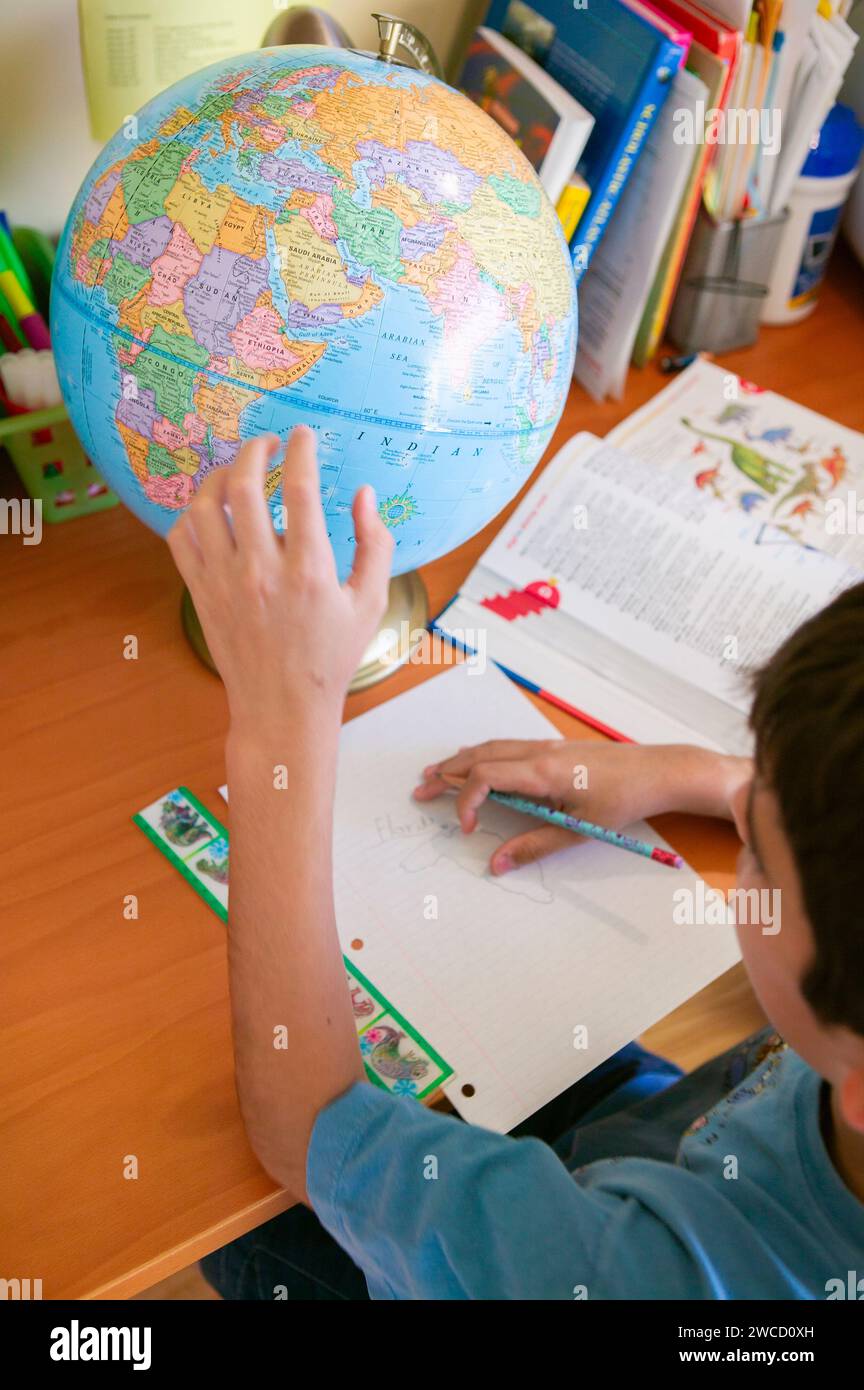 Boy looking at earth globe on a desk Stock Photo - Alamy