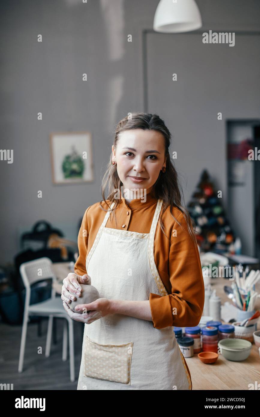 Portrait of a beautiful smiling pottery workshop leader. A middle-aged ...