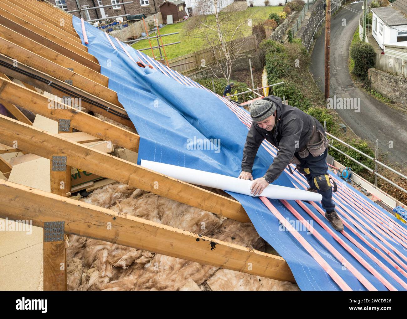 Rolling out felt on a house roof before renewing batons, Llanfoist ...