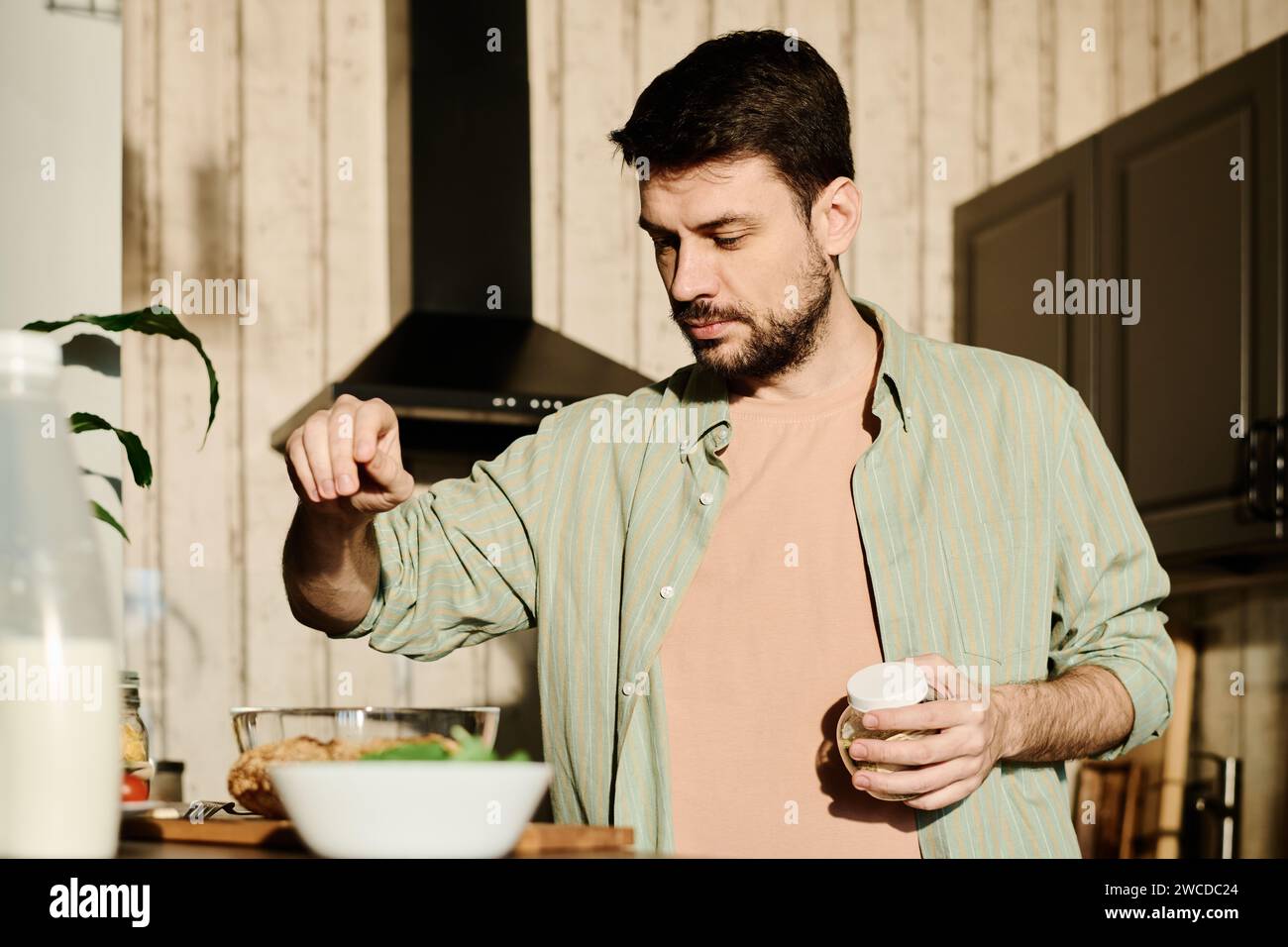 Guy sprinkling sea salt into bowl with broken raw eggs while standing ...