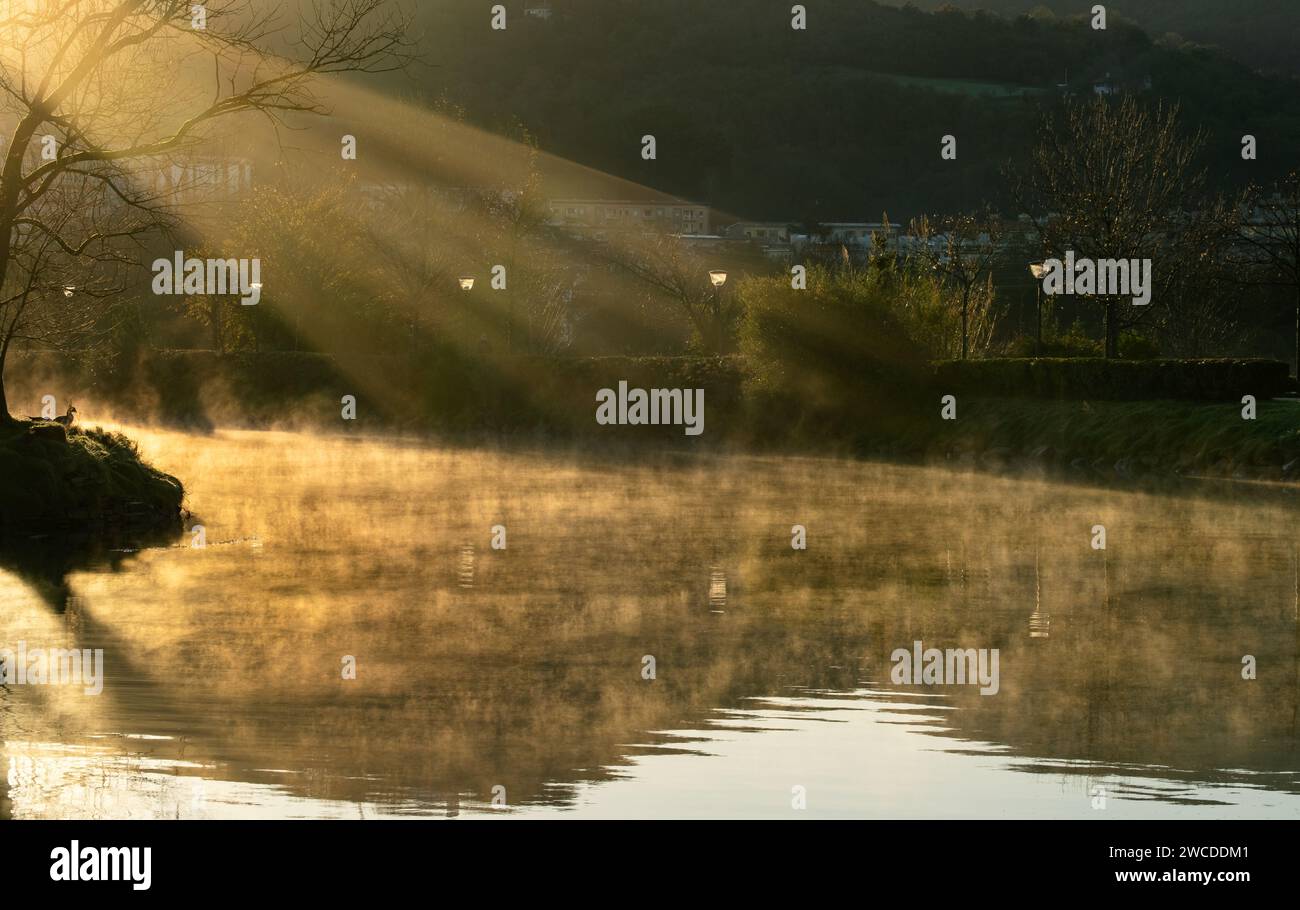 horizontal photograph of a ray of sunlight illuminating a river in the ...