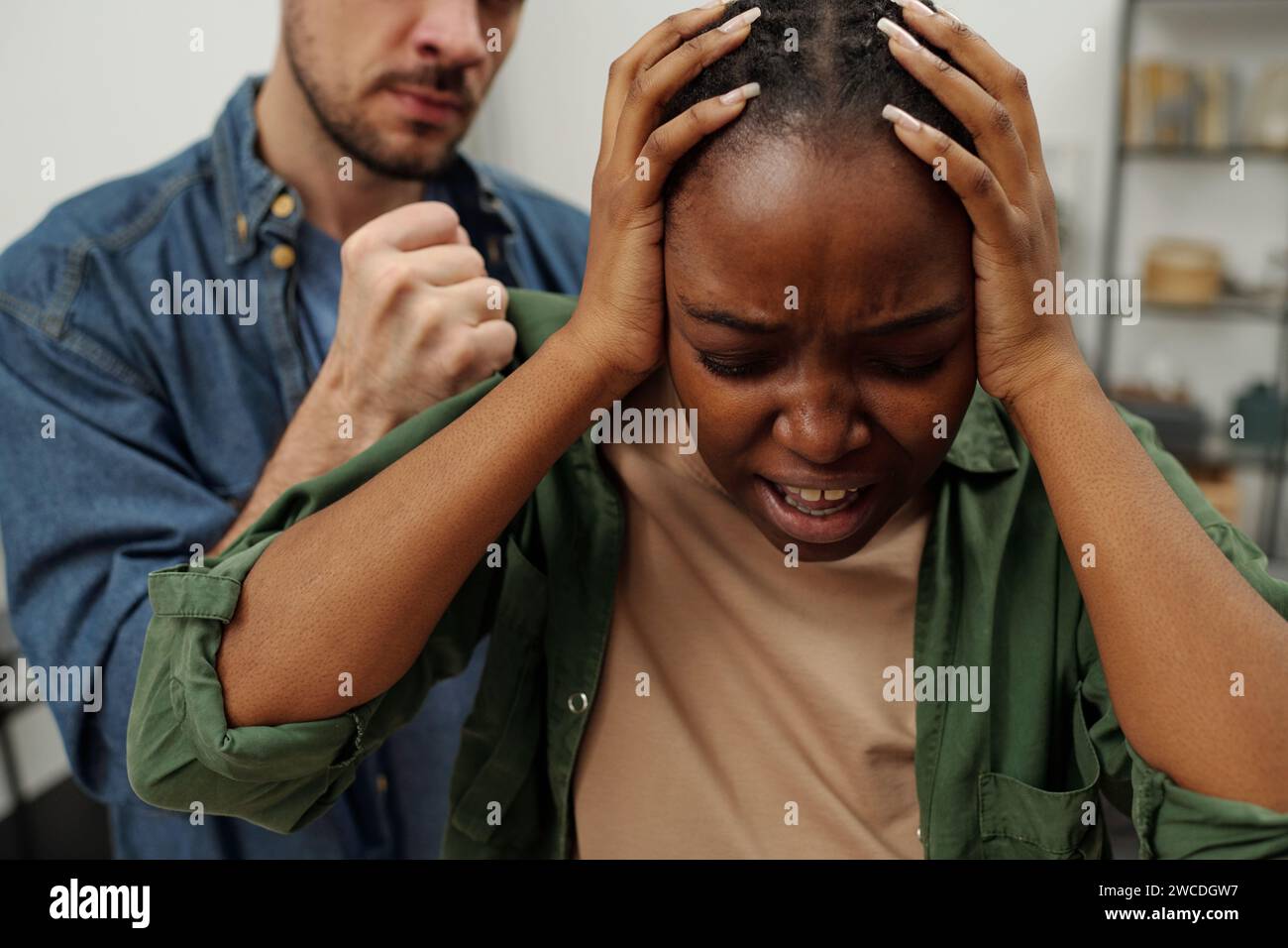 Young helpless African American woman standing against aggressive man ...