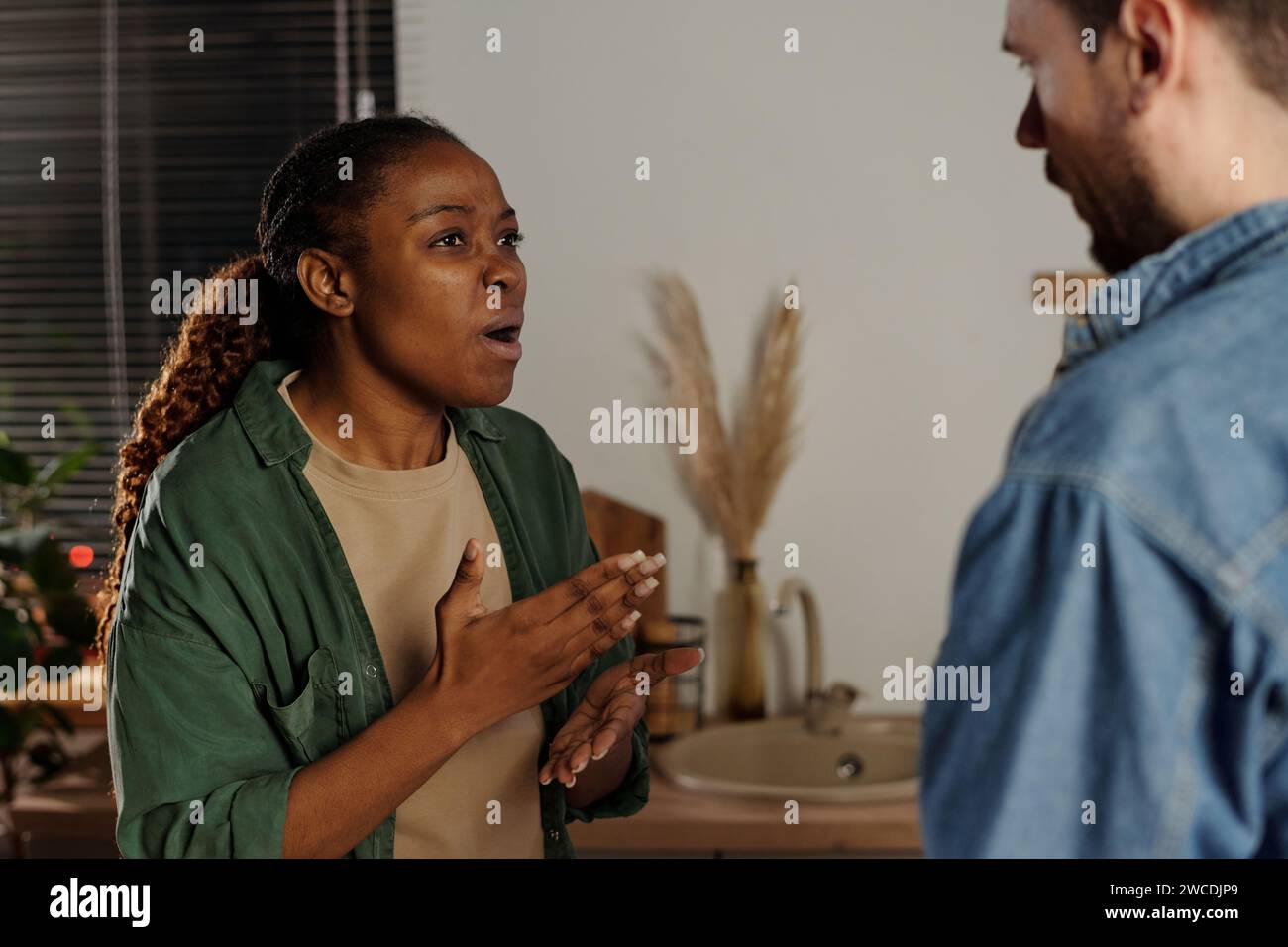 Young emotional woman shouting at her husband while looking at him and ...