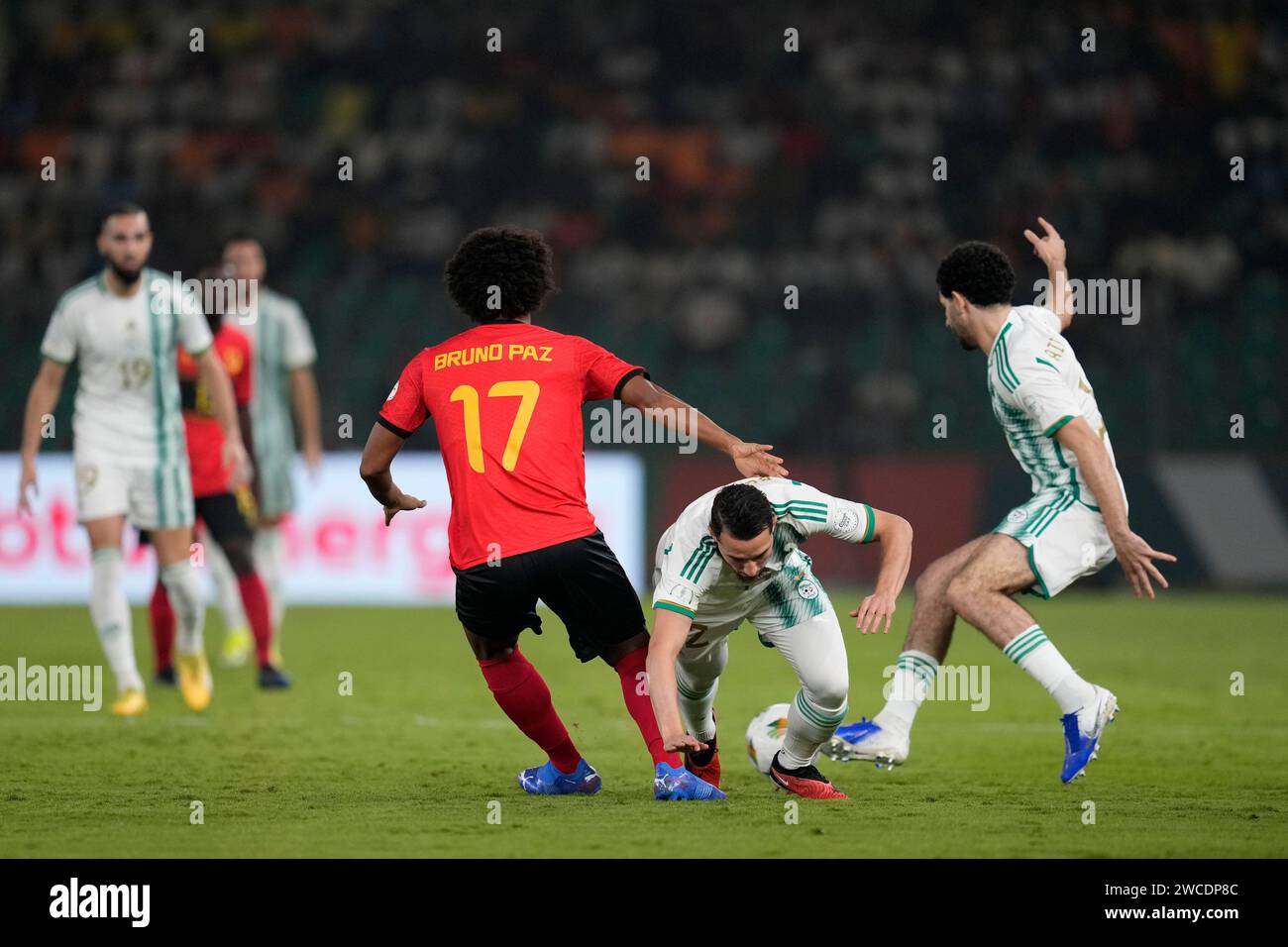 Algeria's Ismael Bennacer, centre, falls in front of Angola's Bruno Paz ...