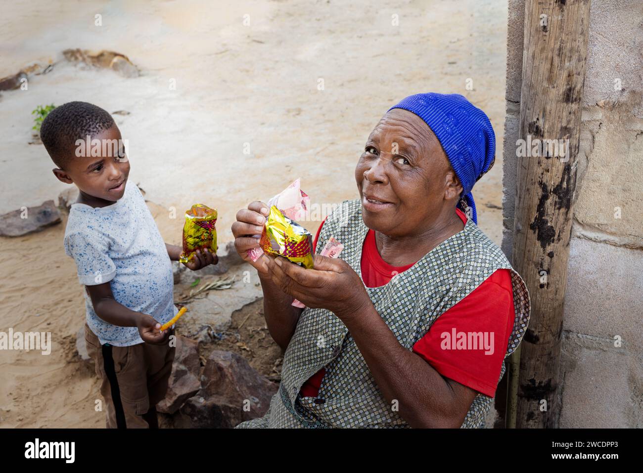 portrait of grandmother and grandson sharing some maize snacks siting ...