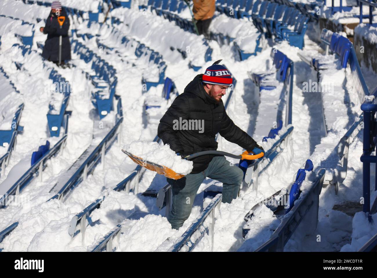 A stadium worker clears snow from seats before an NFL wild-card playoff ...