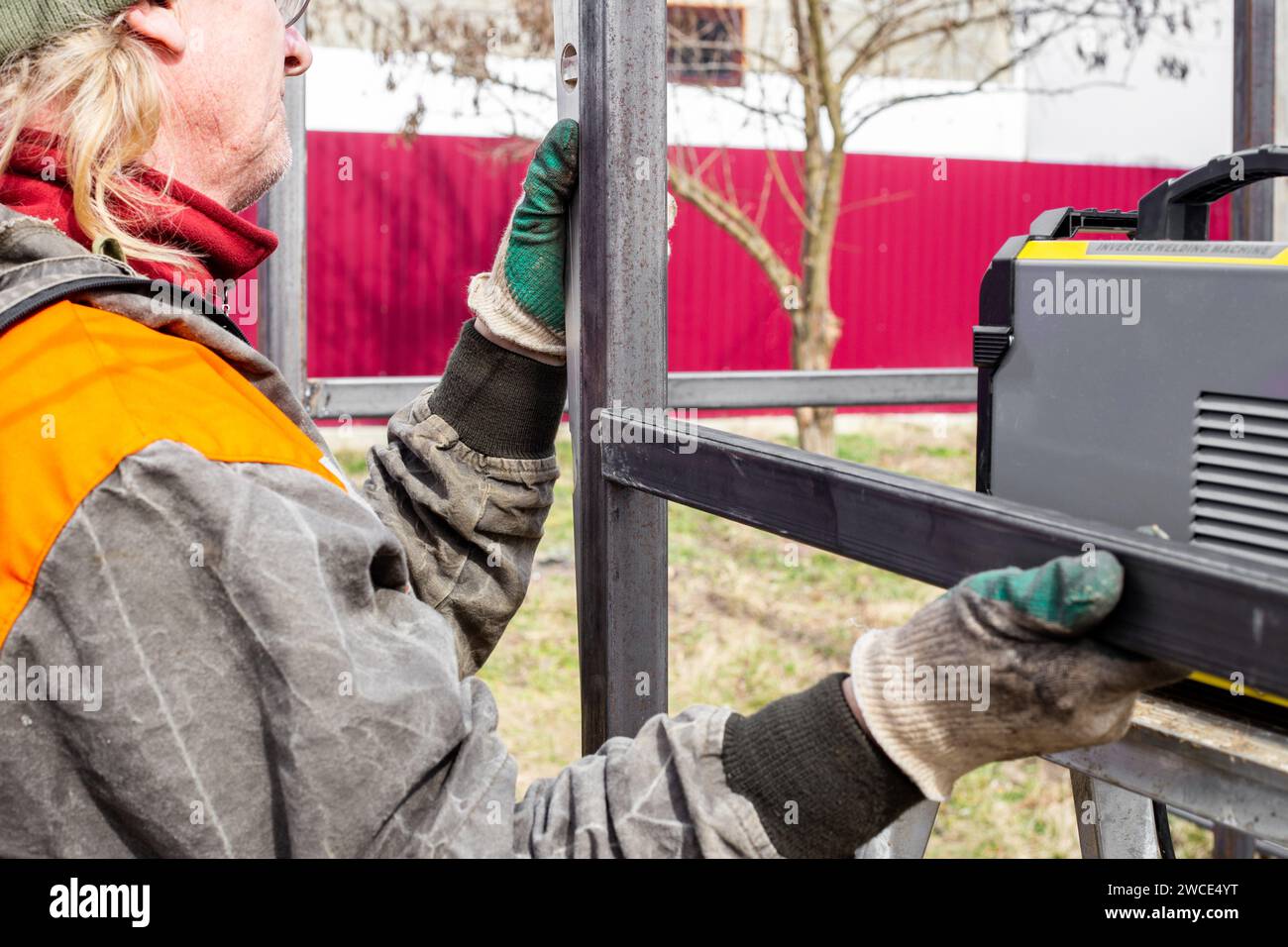 A man installs an iron frame for construction. Welding metal profiles ...