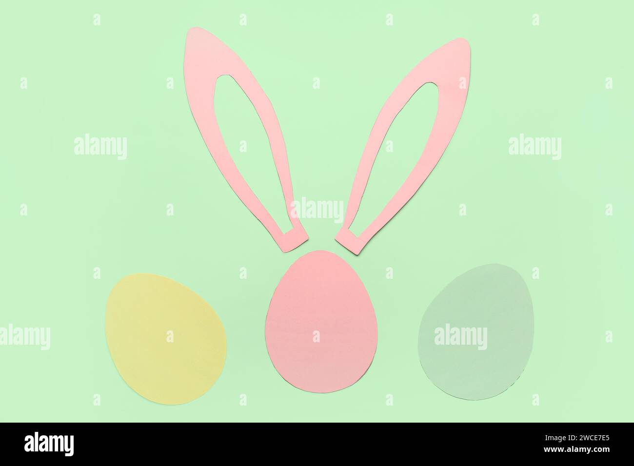 Paper bunny ears and Easter eggs on green background Stock Photo - Alamy