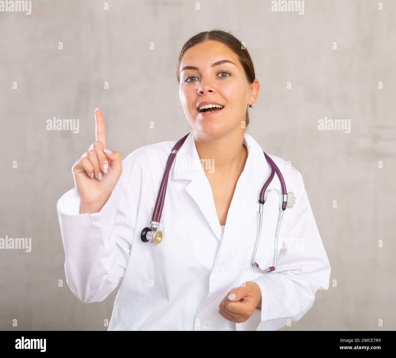Happy young female doctor pointing to side with her finger Stock Photo ...