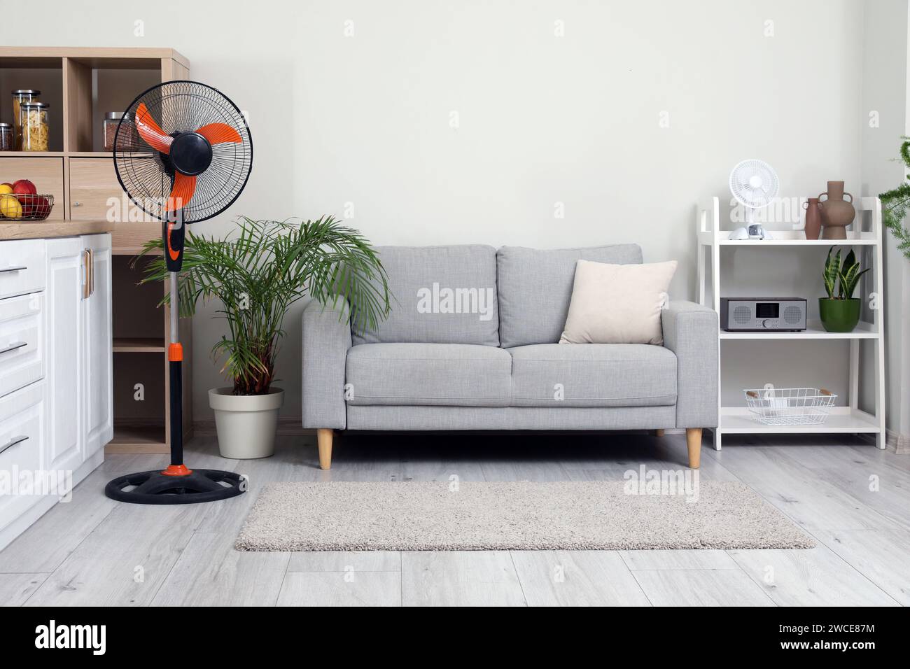 Interior of light living room with grey sofa and modern floor fan Stock ...