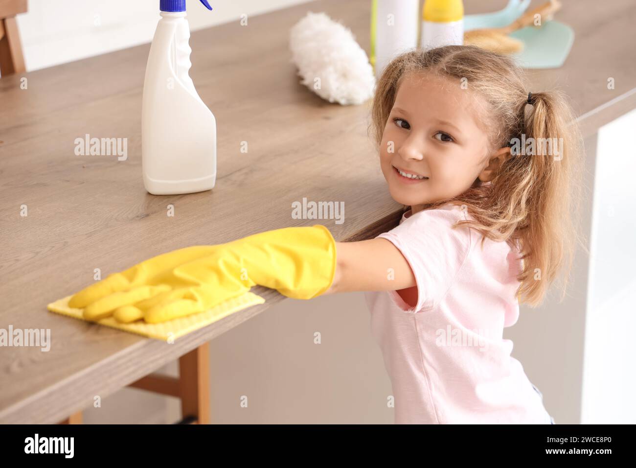 Cute little girl cleaning table in kitchen Stock Photo - Alamy