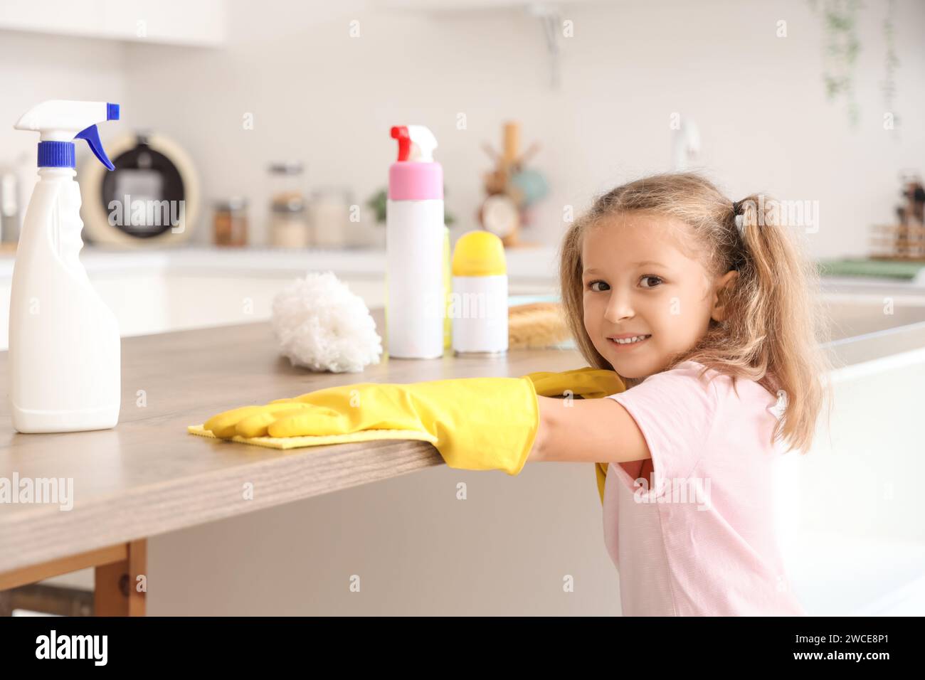 Cute little girl cleaning table in kitchen Stock Photo - Alamy
