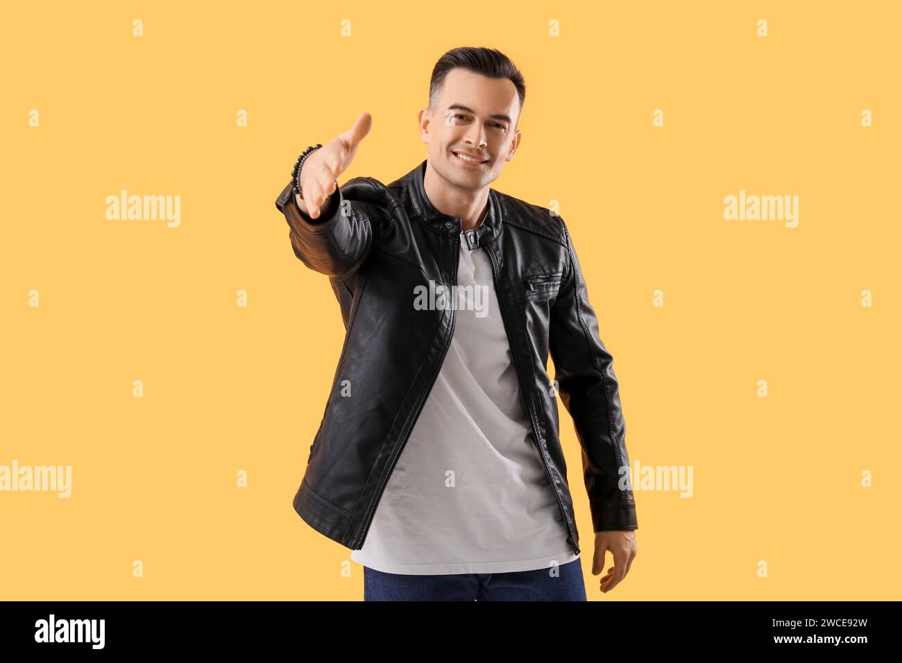 Young man reaching out for handshake on yellow background Stock Photo ...