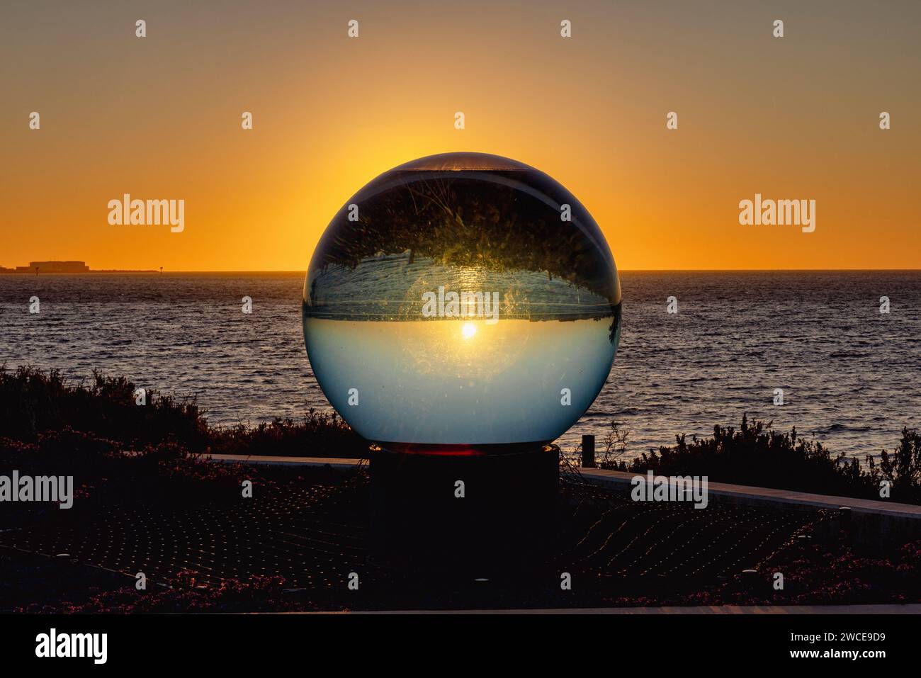 A transparent glass sphere is placed gracefully atop a verdant field ...