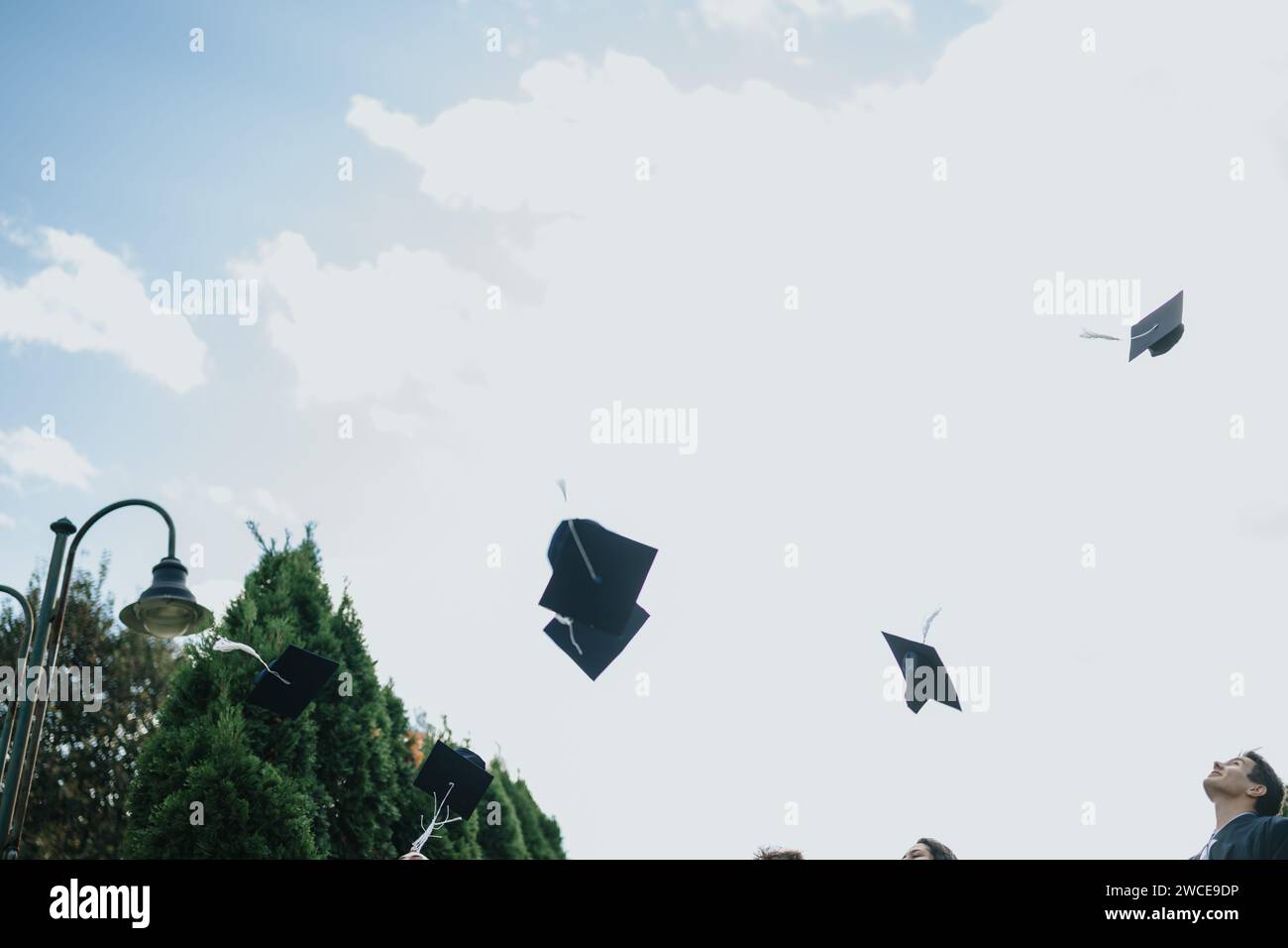 Students wearing gowns throwing caps in the air as they create ...