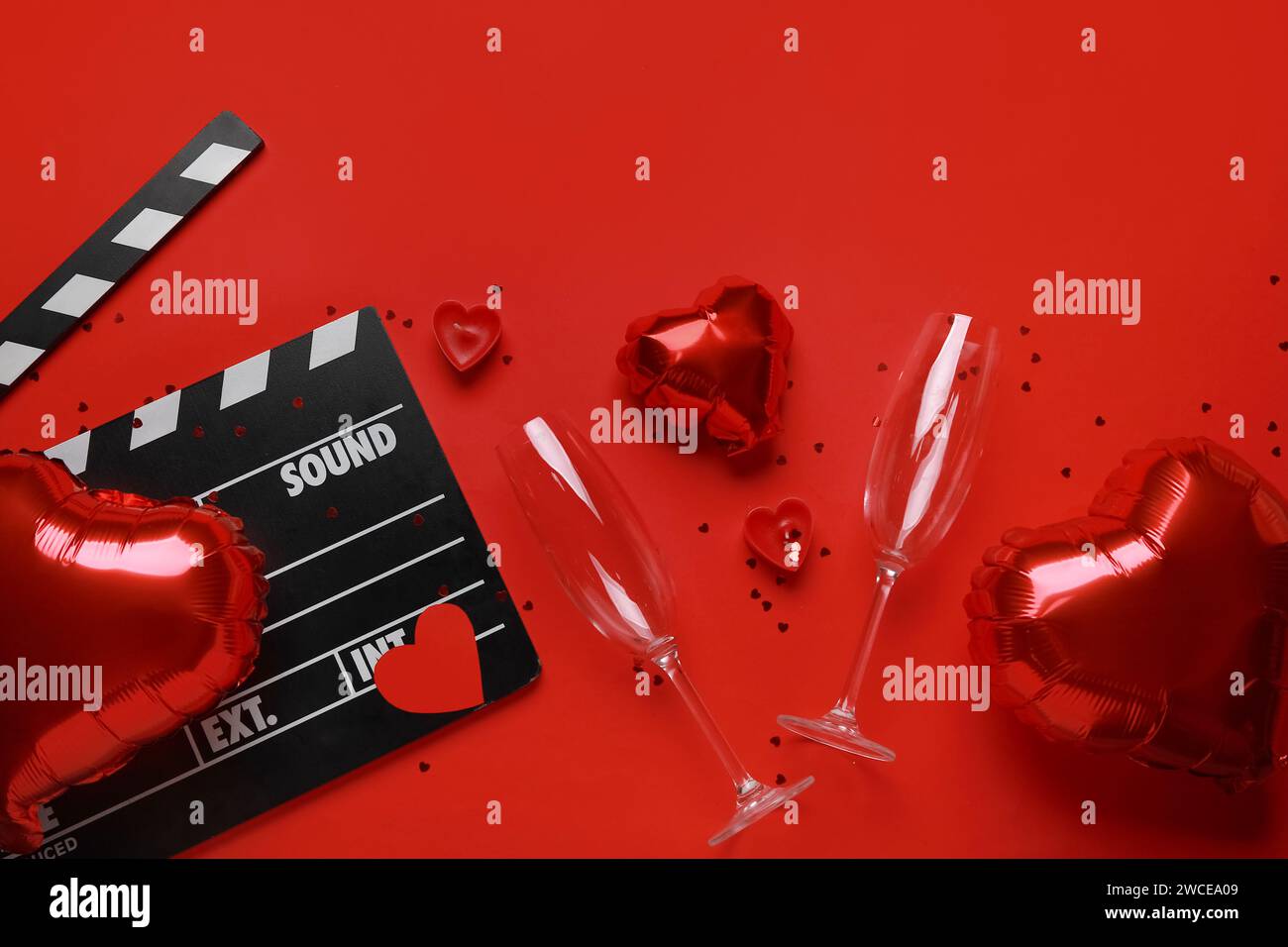 Movie clapper with heart shaped air balloons, candles and champagne ...
