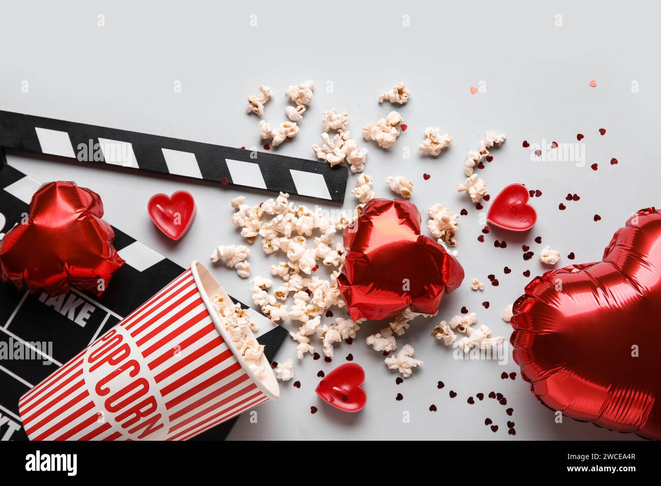 Movie clapper with bucket of popcorn and heart shaped decor on white ...