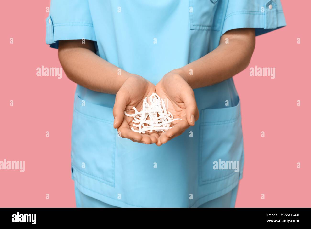Female dentist with floss toothpicks on pink background Stock Photo - Alamy