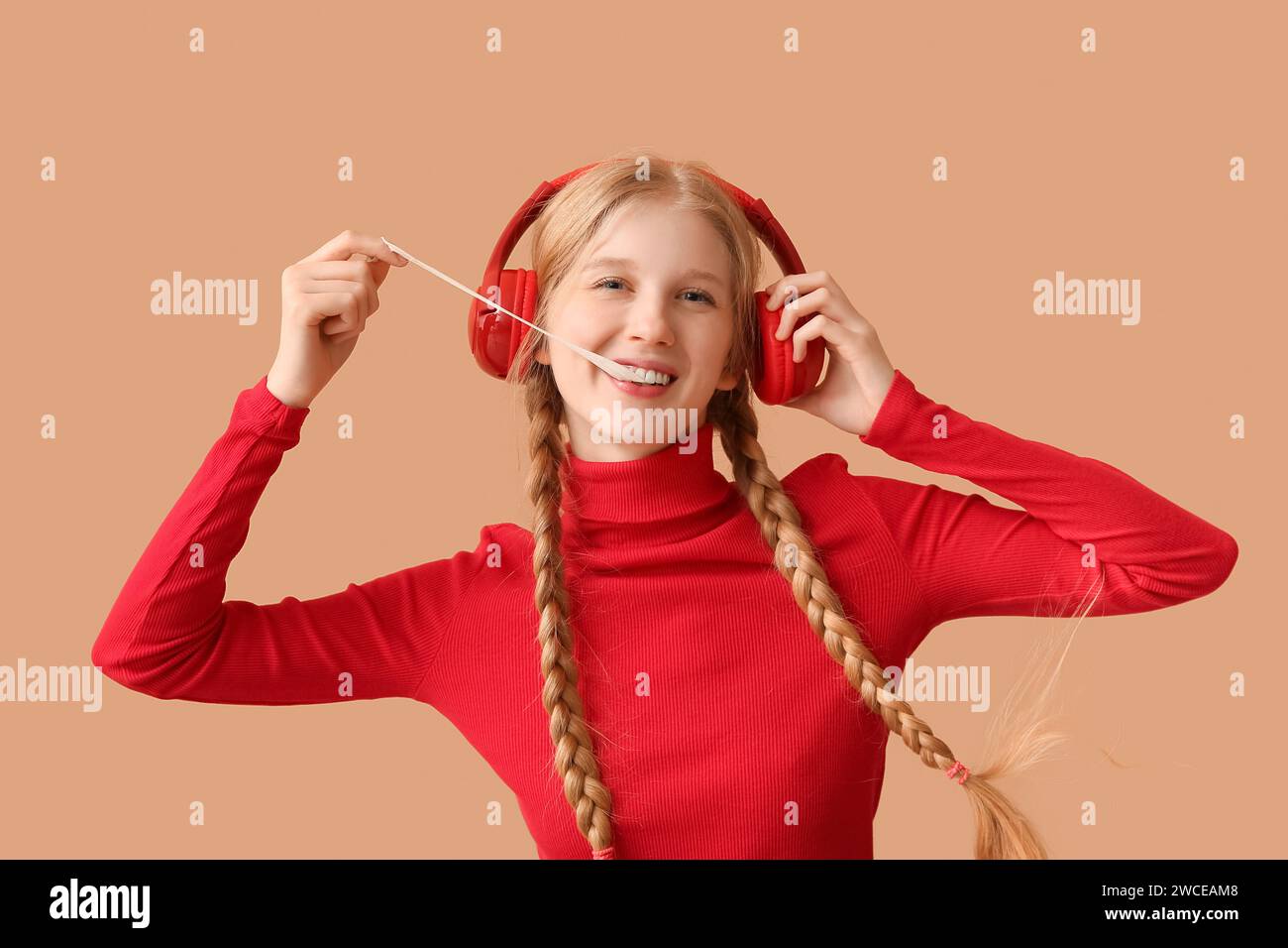Teenage girl in headphones chewing gum on beige background Stock Photo ...