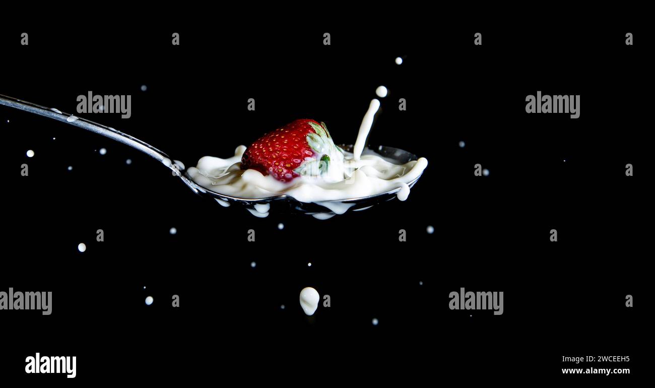 Strawberry splashing into a milky liquid in a spoon Stock Photo - Alamy