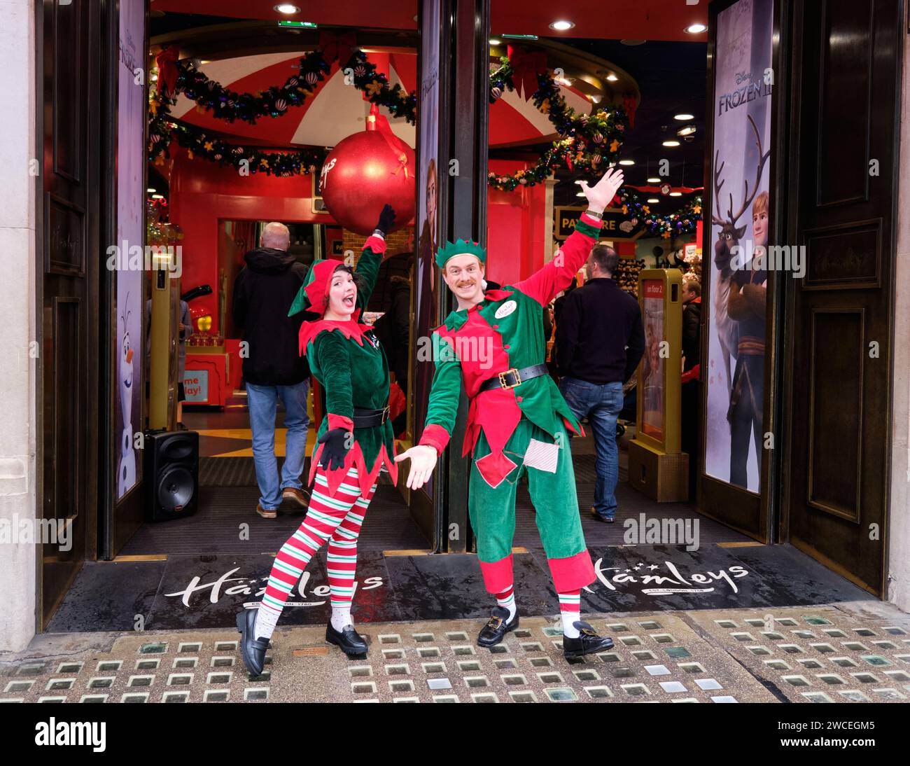two elves in festive costumes greeting customers before Christmas at ...