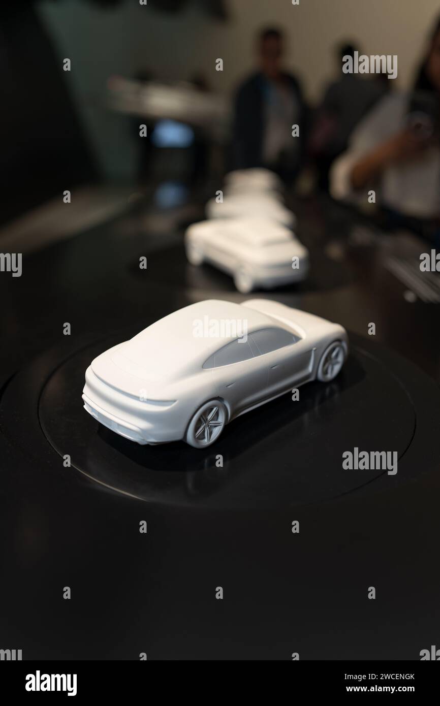 A miniature model of a Porsche car. White car models are displayed as ...