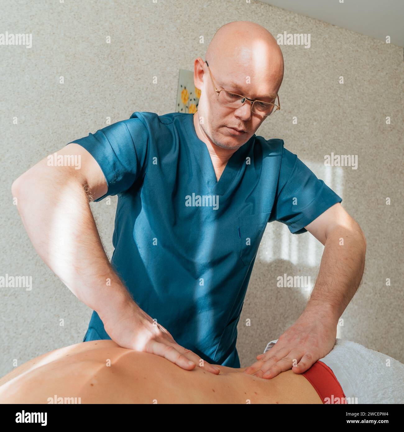 Massage therapist with strong hands and fingers kneads muscles of ...