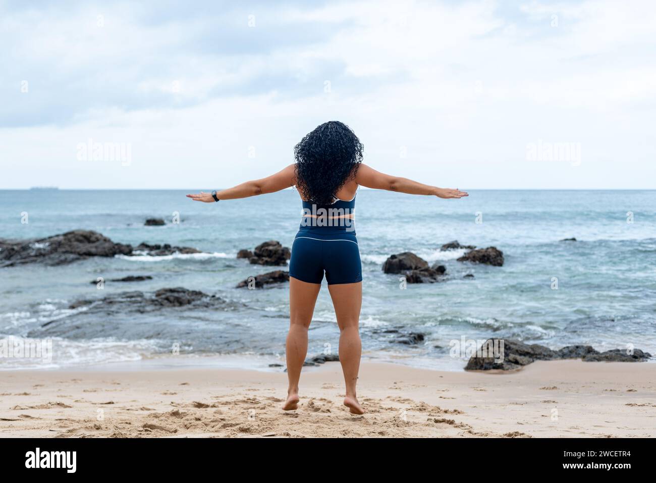 Fitness woman, athlete, doing jumping jacks on the beach sand. Healthy ...