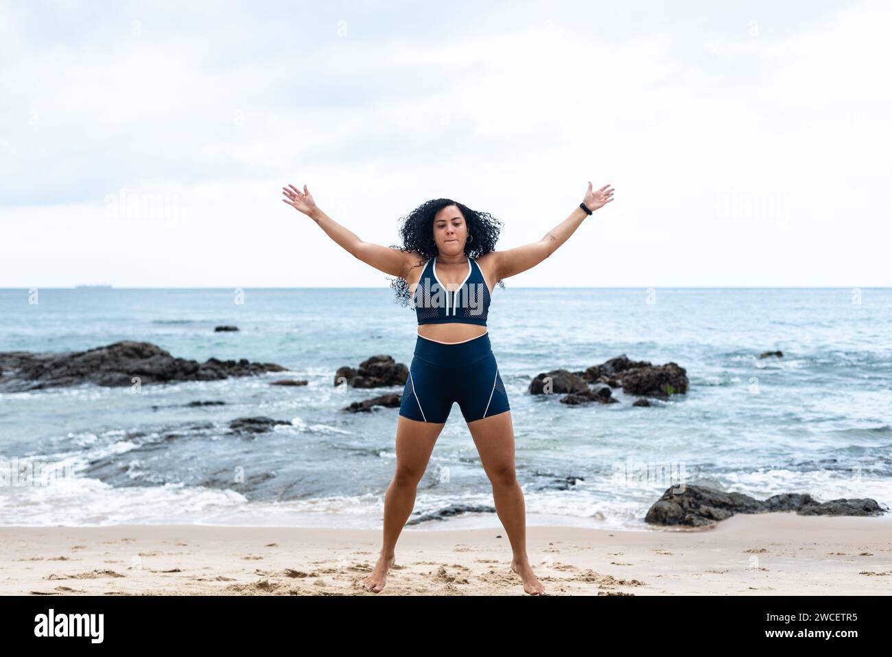 Fitness woman, athlete, doing jumping jacks on the beach sand. Healthy ...