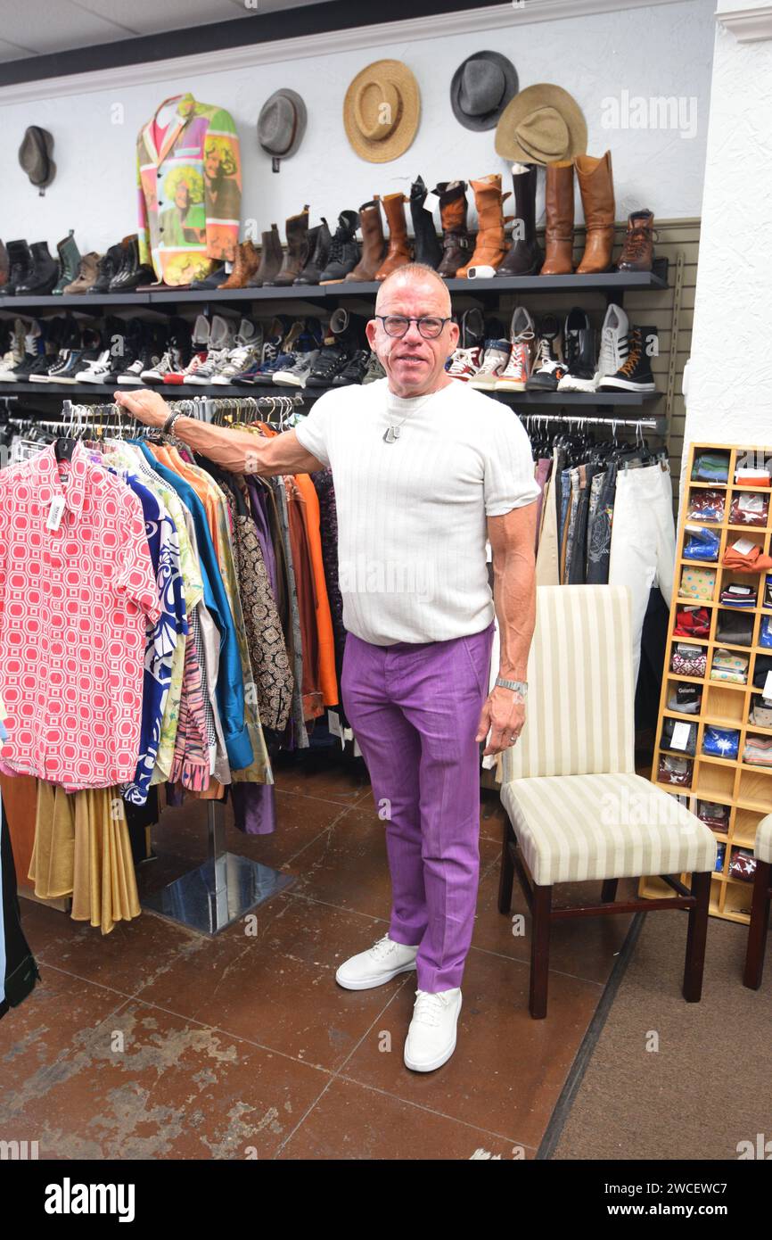 LGBT man posing inside his clothing consignment store, standing next to ...