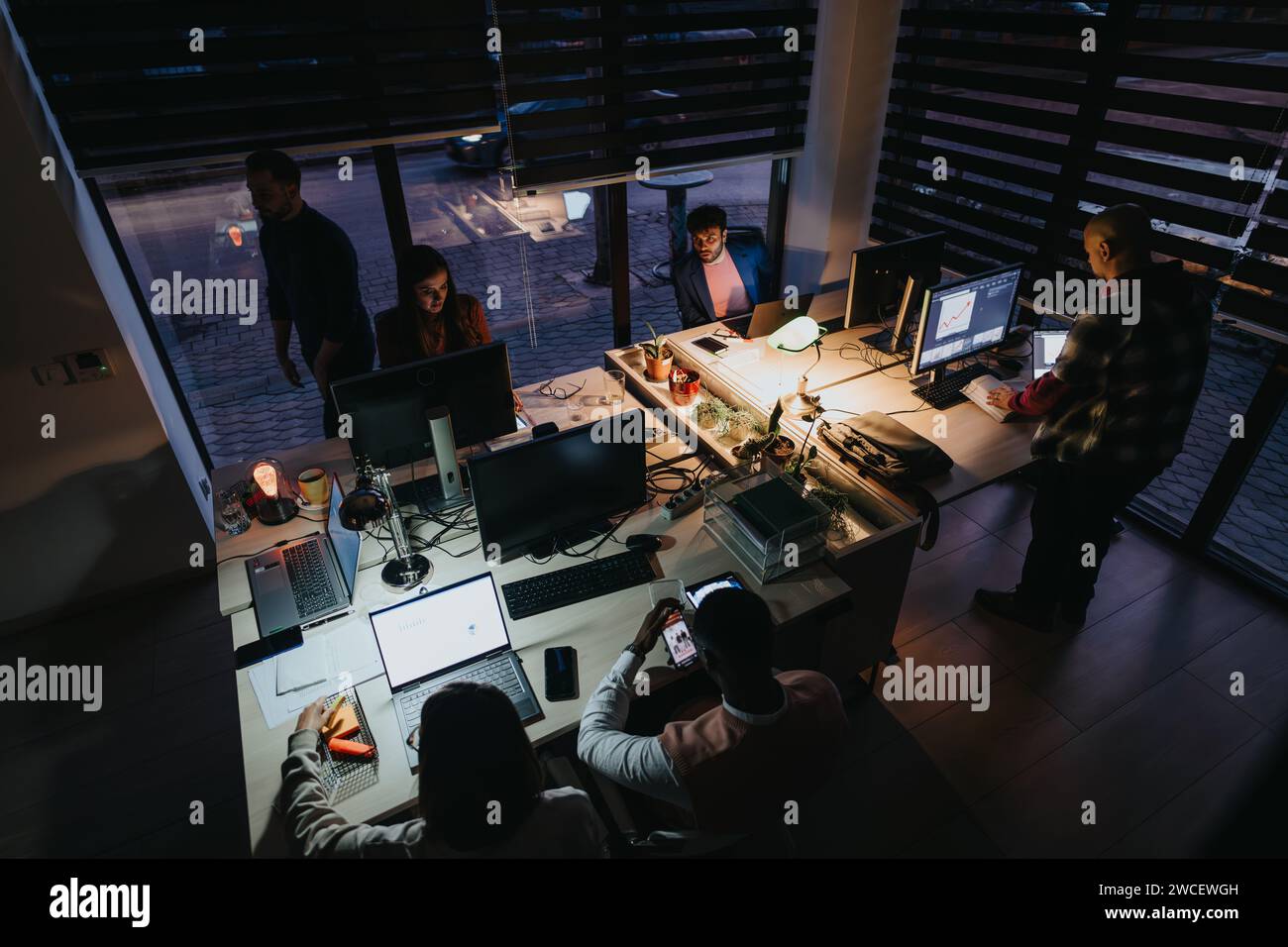 Diverse business team working late into the night, collaborating and ...