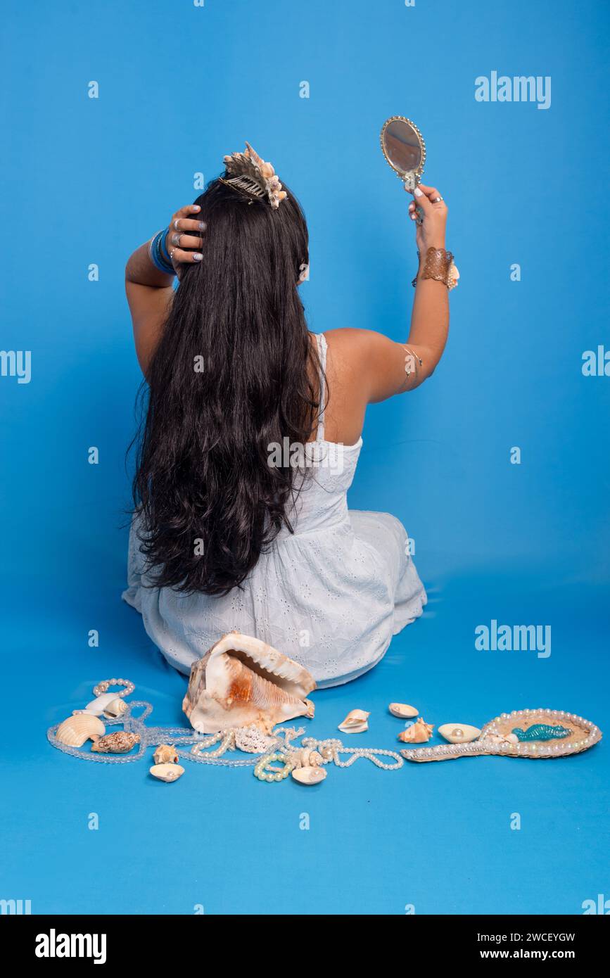 Beautiful black-haired woman wearing white clothing, sitting against ...