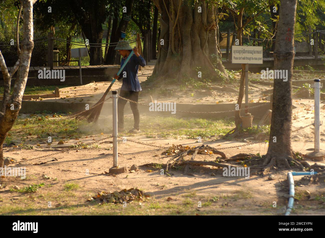 Ladies sweep leaves around a Killing Tree at the Killing Fields of ...