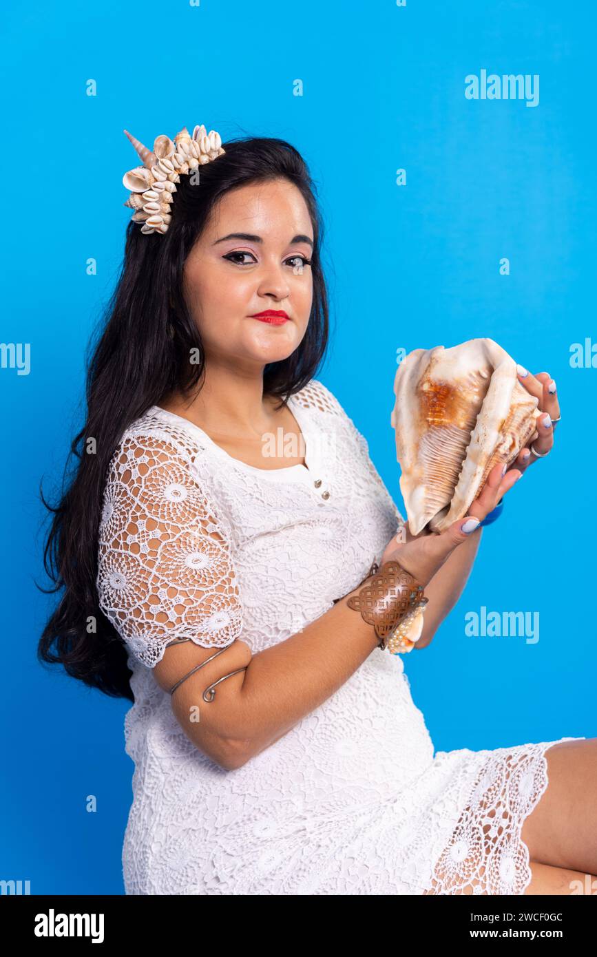 Beautiful, black-haired woman wearing white clothing, sitting holding a ...