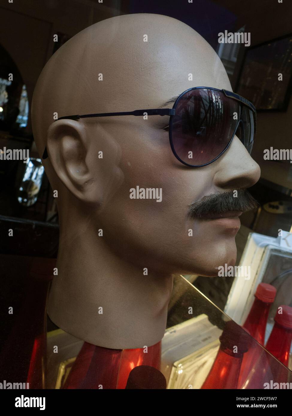 A stylish bald mannequin head dons a pair of chic sunglasses, adding a ...