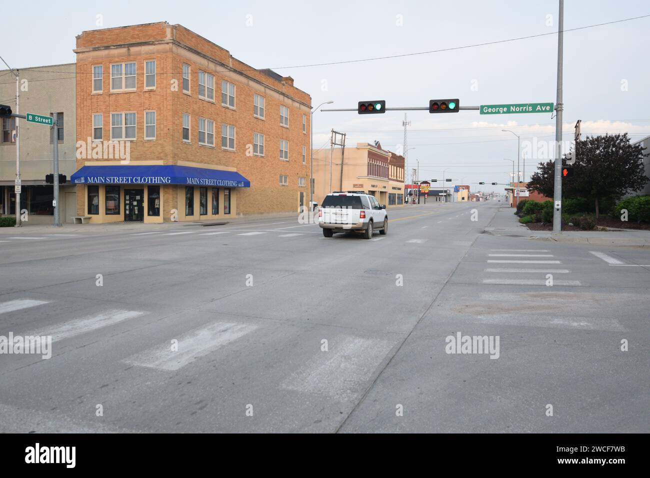 A white SUV driving past a green light and Main Street Clothing store ...