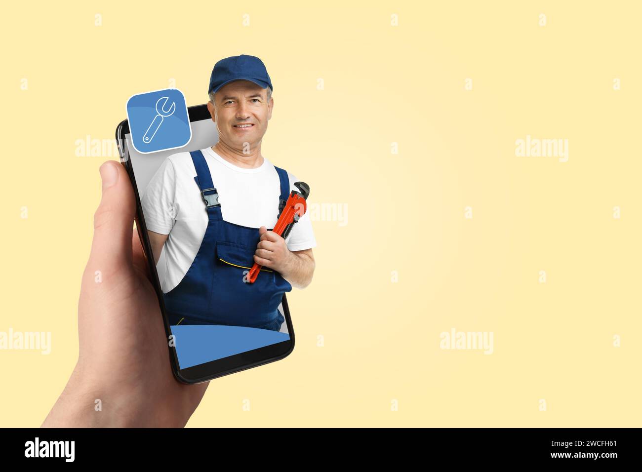 Find plumber. Man using mobile phone on light yellow background ...