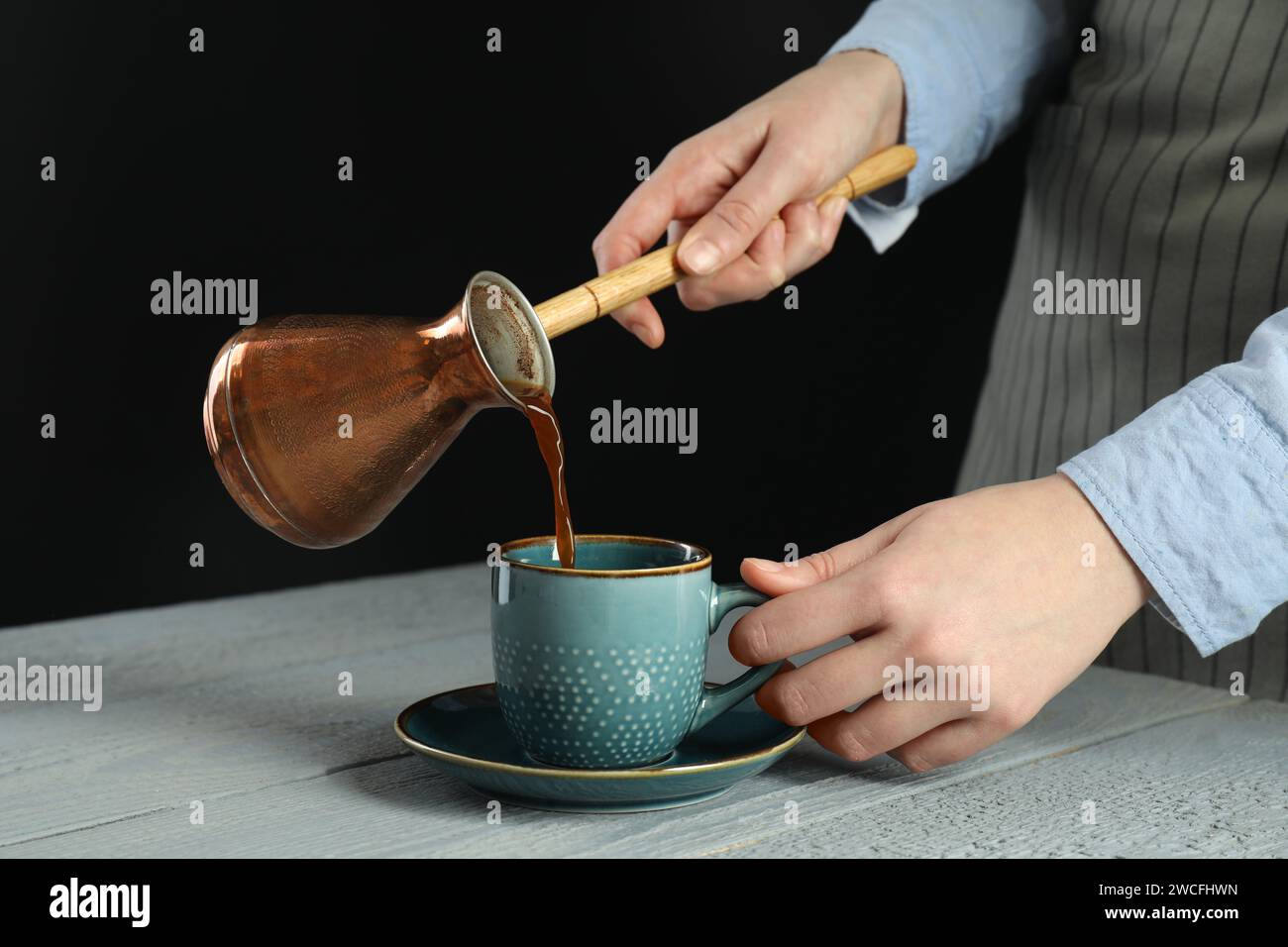 Turkish coffee. Woman pouring brewed beverage from cezve into cup at ...