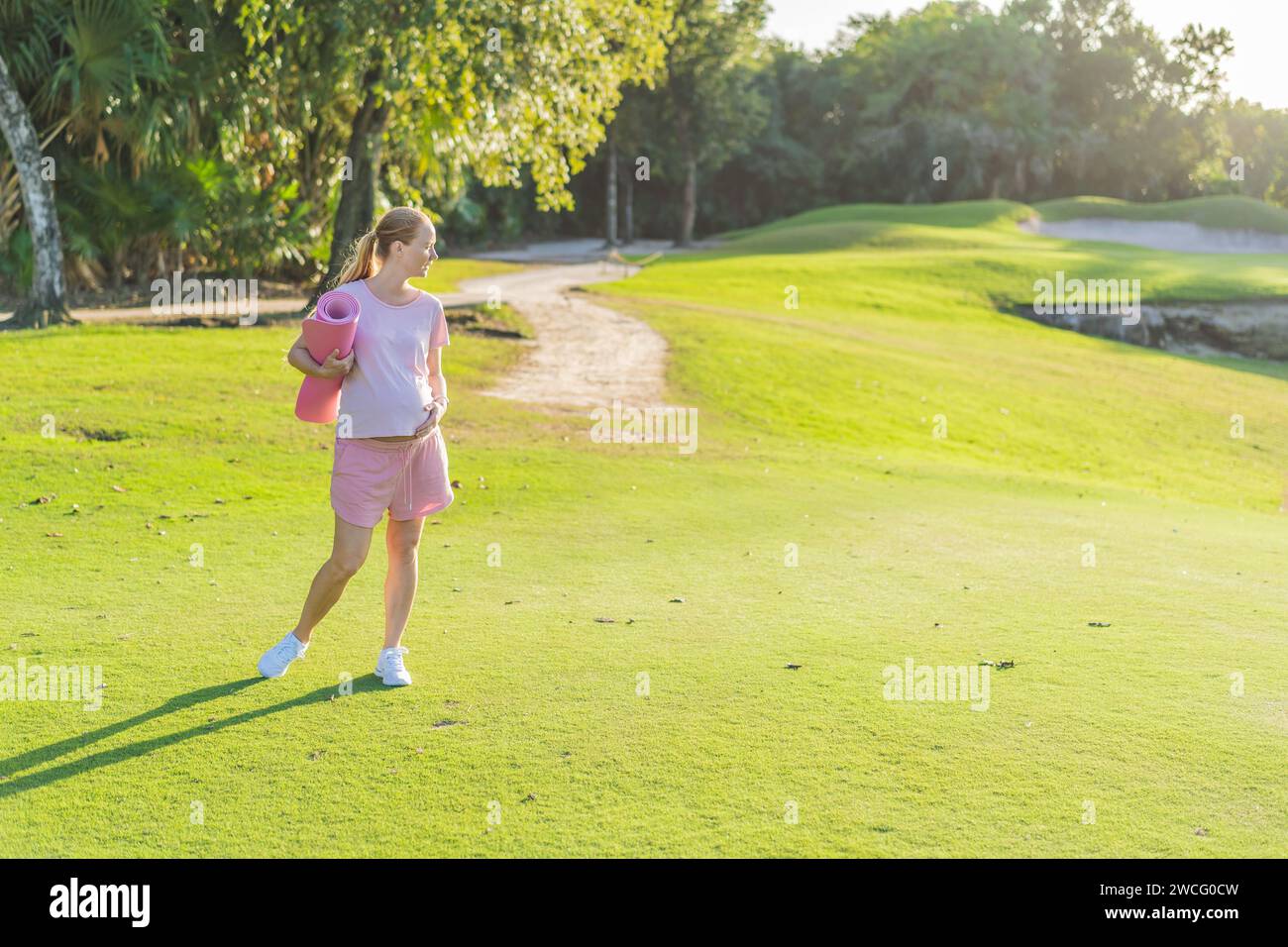 Energetic pregnant woman takes her workout outdoors, using an exercise ...