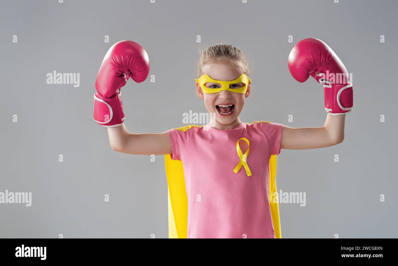 Child in boxing gloves with a yellow ribbon as a symbol of the fight ...