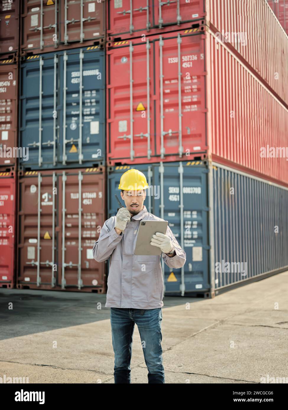 Asian worker wearing safety helmet and using walkie talkie communicate ...