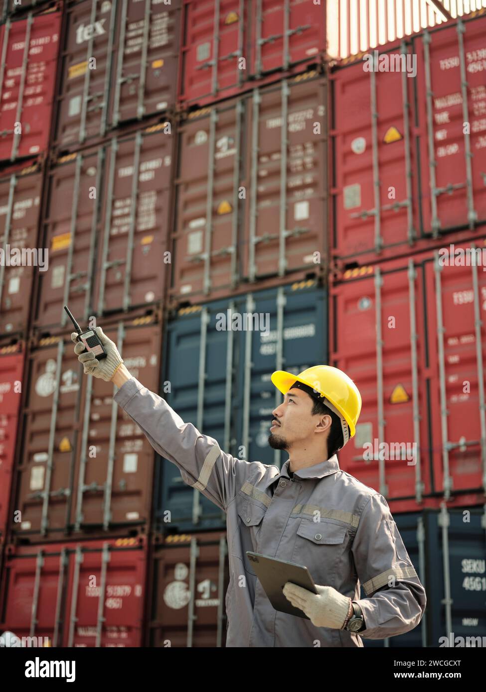 Asian worker wearing safety helmet and using walkie talkie in front of ...