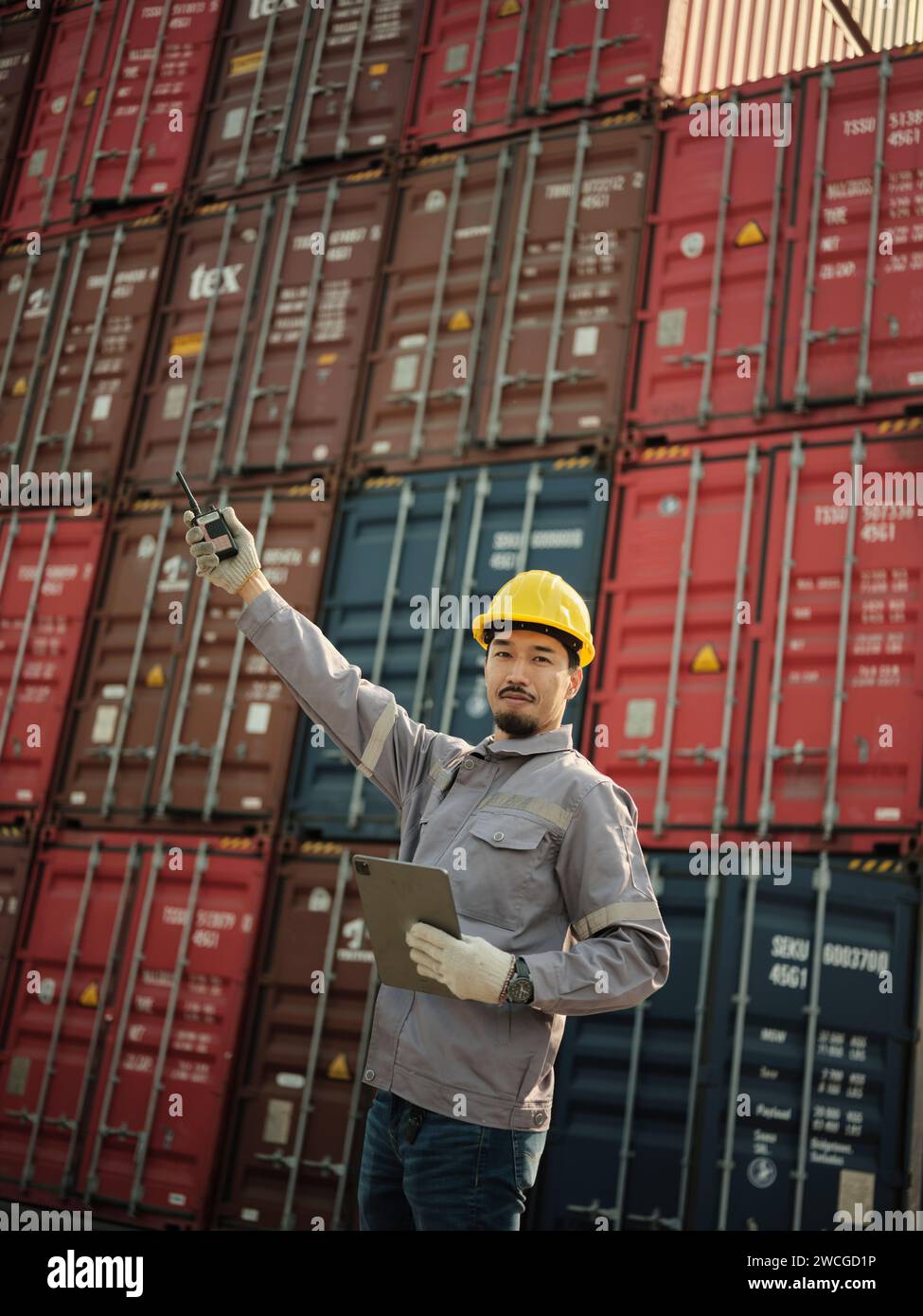 Asian worker wearing safety helmet and using walkie talkie in front of ...
