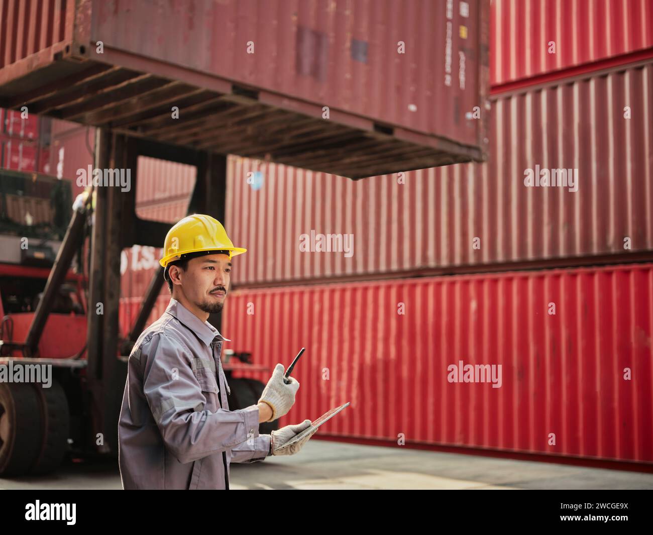 Asian worker wearing safety helmet and using walkie talkie communicate ...