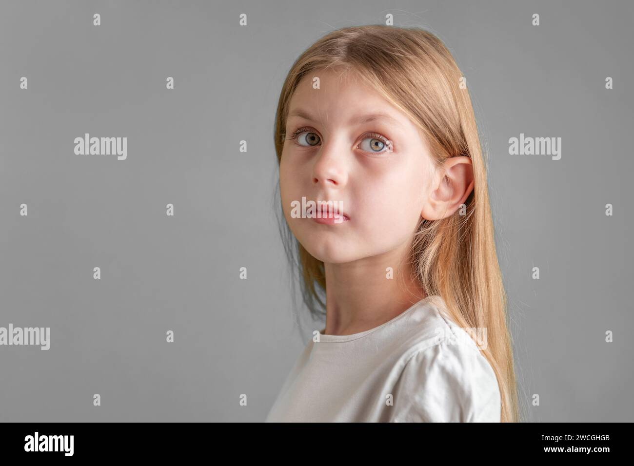 Portrait of cute little girl with long light hair in white t-shirt ...