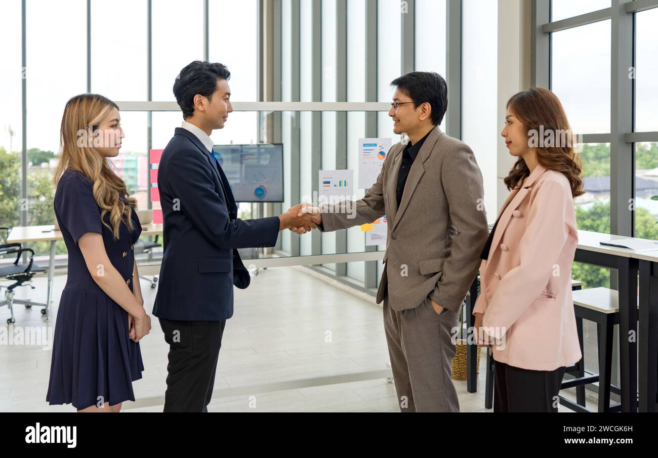 Corporate professional in formal attire engaged in a handshake during a ...