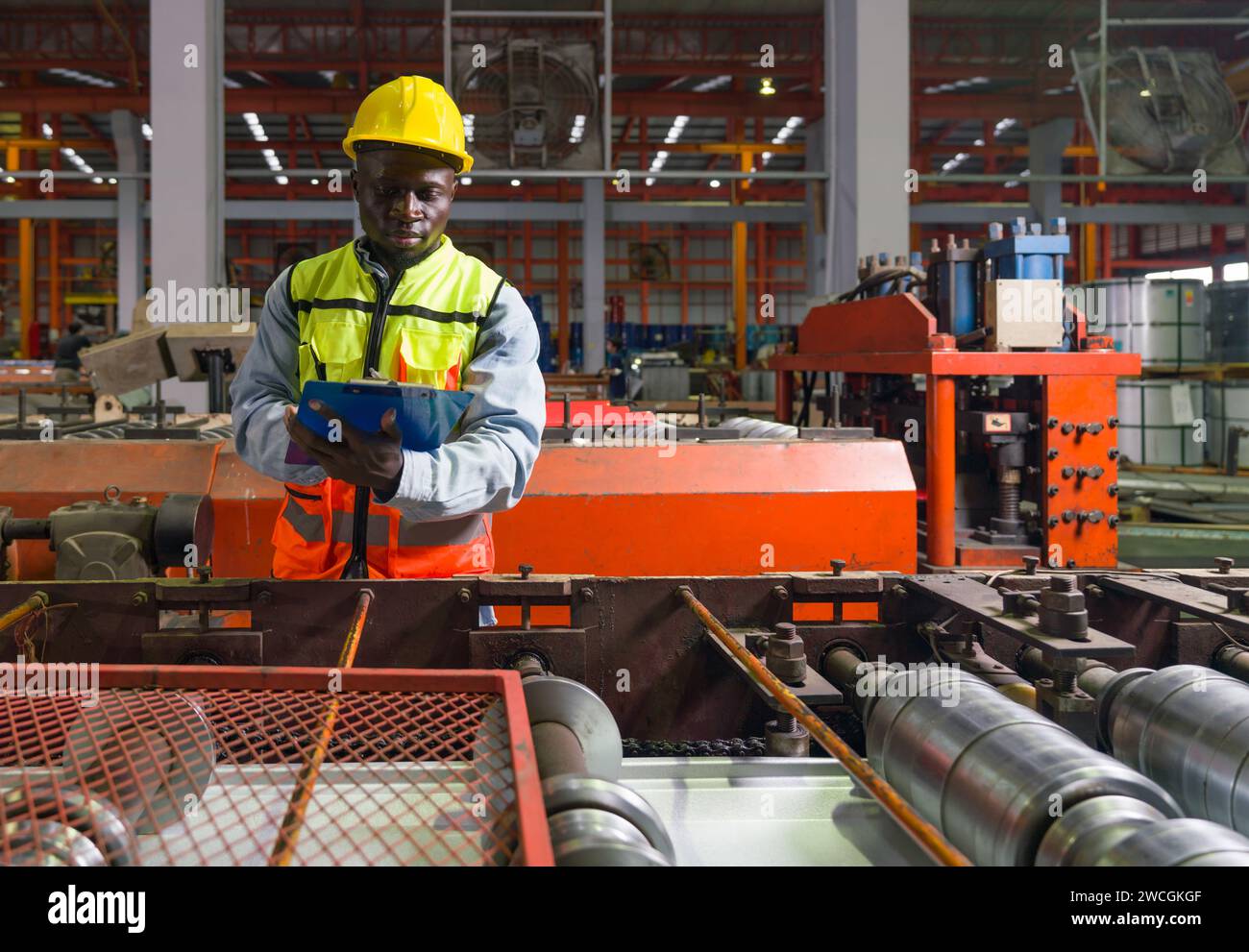 A factory worker is standing on a production line conveyor belt ...